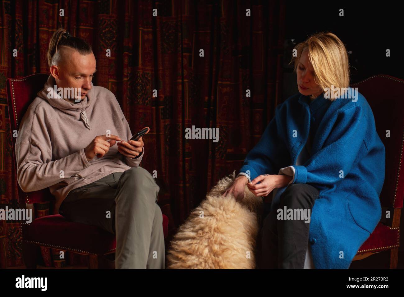 A man and a woman are having a dialogue. A dog is sitting next to him ...