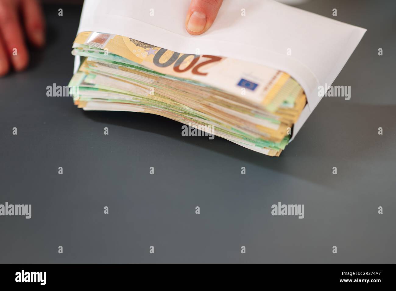 Euro bills in an envelope on a gray background.Hands recalculate ...
