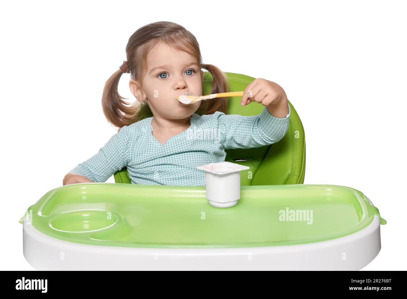Cute little child eating tasty yogurt from plastic cup with spoon in ...