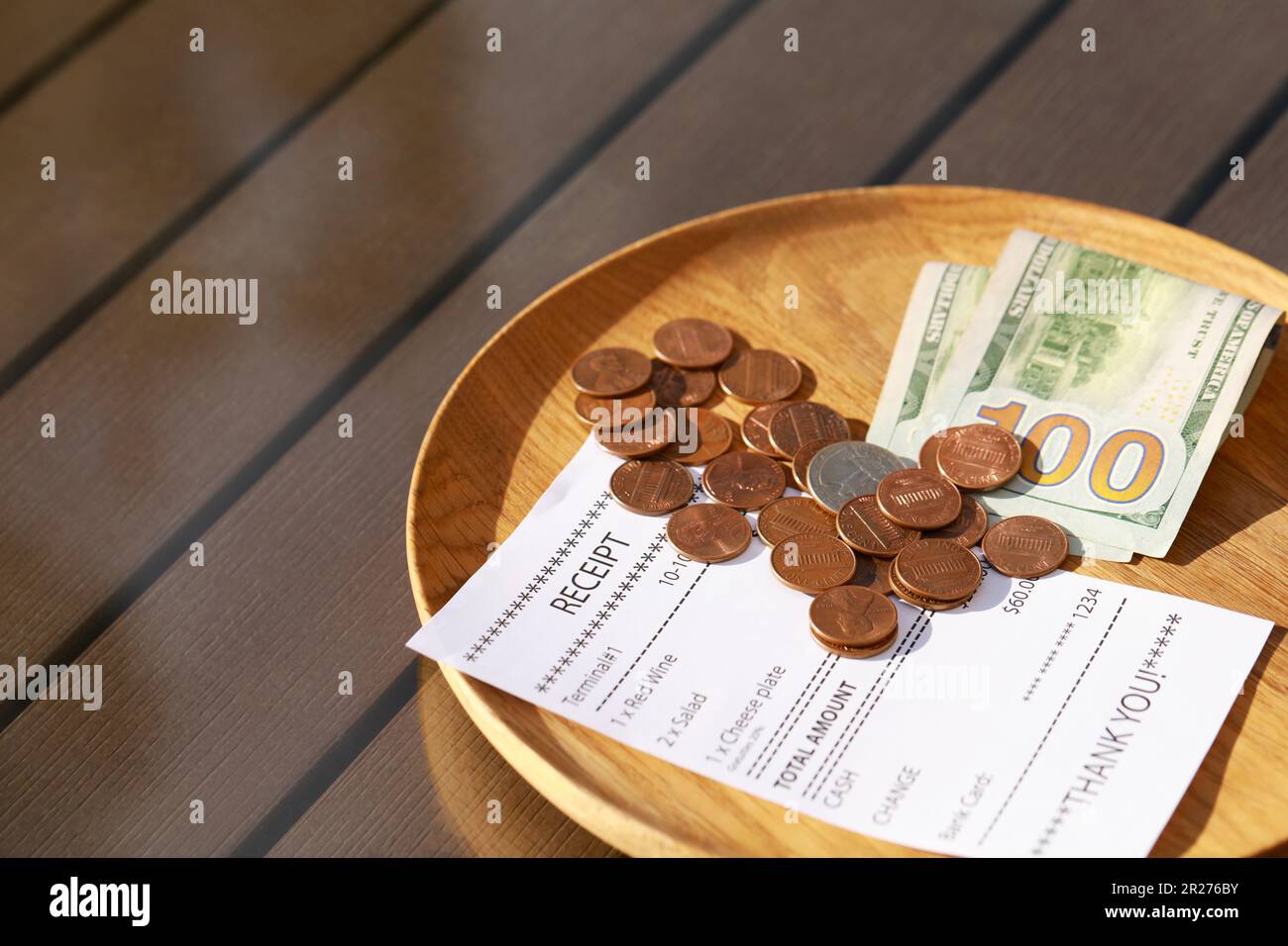 Wooden plate with payment for order and receipt on table, closeup ...