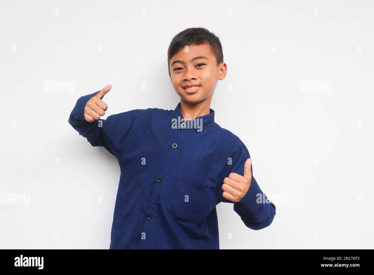 Smiling confident boy wearing a blue casual shirt looking at the camera ...