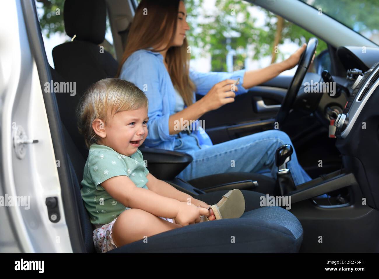 Mother with cigarette and child in car, focus on little girl. Don't ...