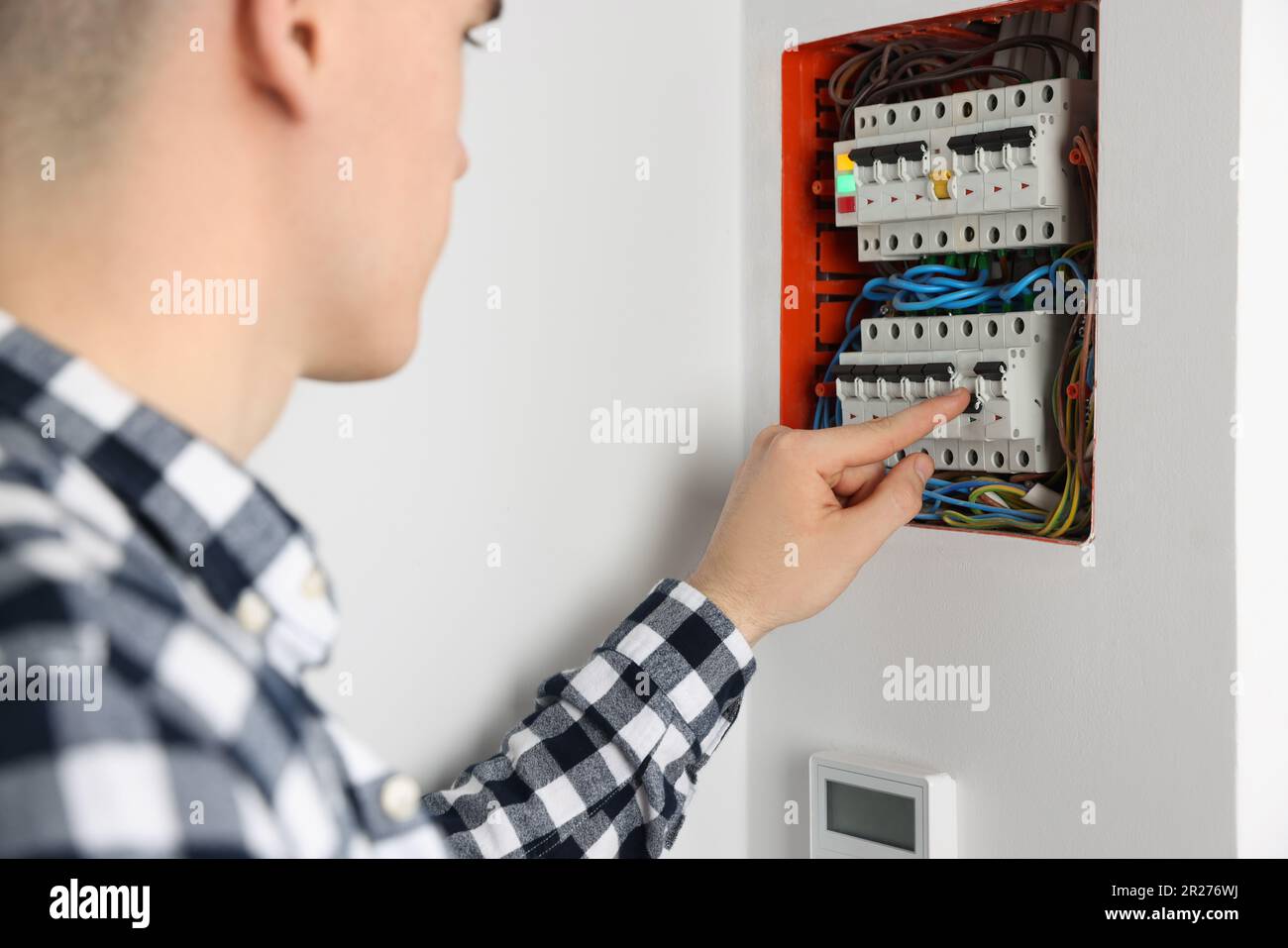 Young handyman pressing switch on electrical panel board indoors Stock ...