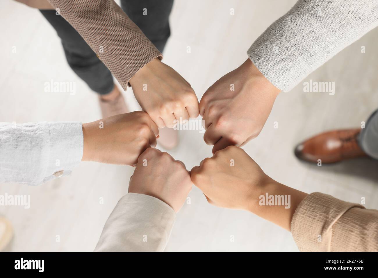 Group of people holding fists together indoors, above view. Unity ...