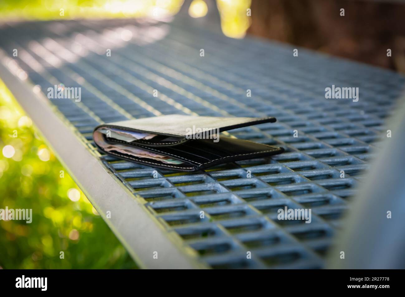 Black wallet on metal bench outdoors. Lost and found Stock Photo - Alamy