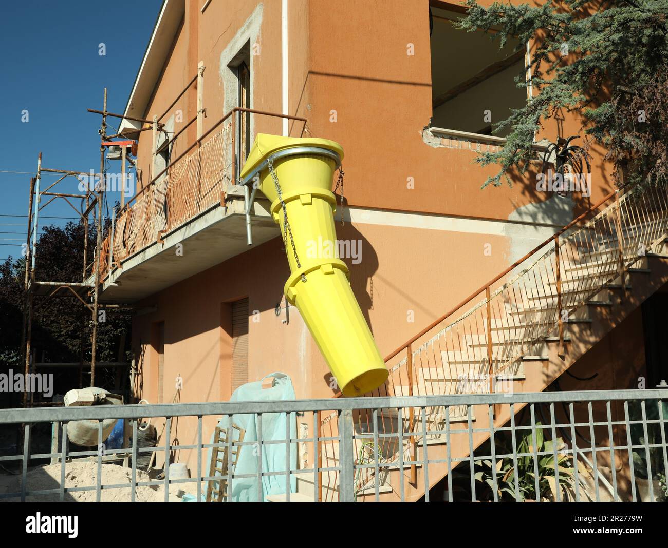 Building with yellow rubble chute outdoors on sunny day Stock Photo - Alamy