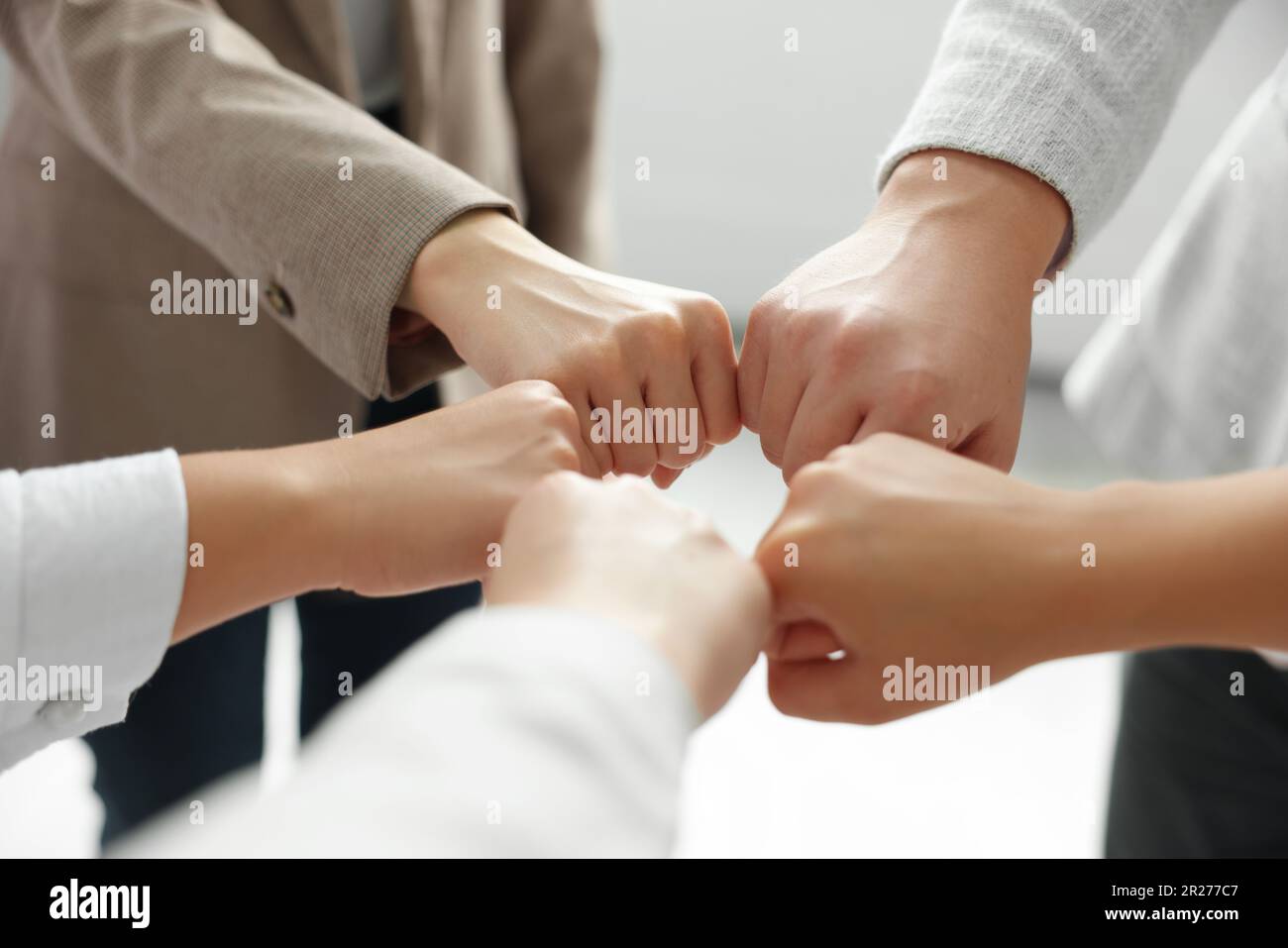 Group of people holding fists together indoors, closeup. Unity concept ...