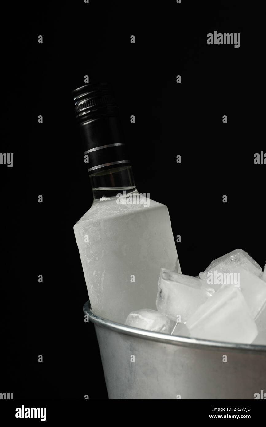 Bottle of vodka in metal bucket with ice on black background Stock ...
