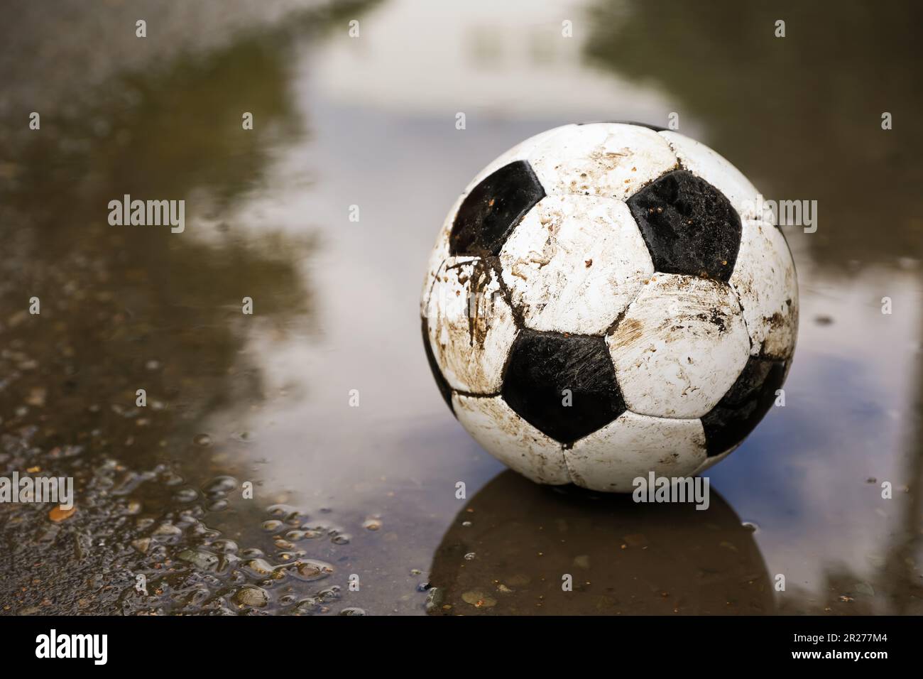 Dirty soccer ball near puddle outdoors, space for text Stock Photo - Alamy
