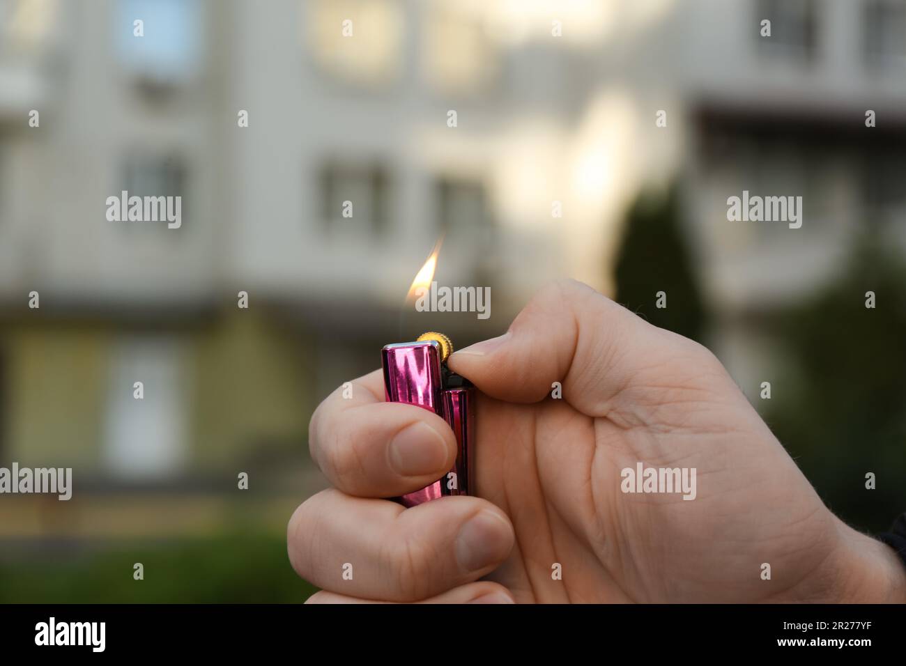 Man holding lighter with burning flame outdoors, closeup Stock Photo ...