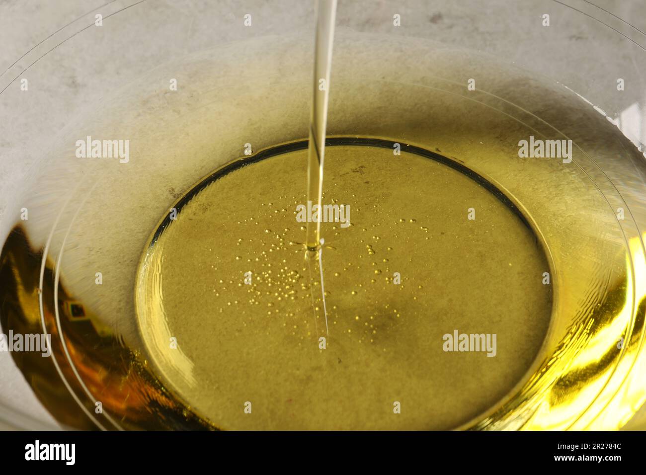 Pouring cooking oil into glass bowl, closeup Stock Photo - Alamy