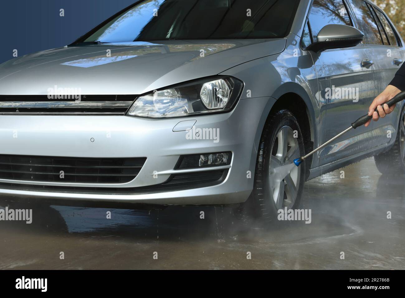 Man washing auto with high pressure water jet at outdoor car wash ...