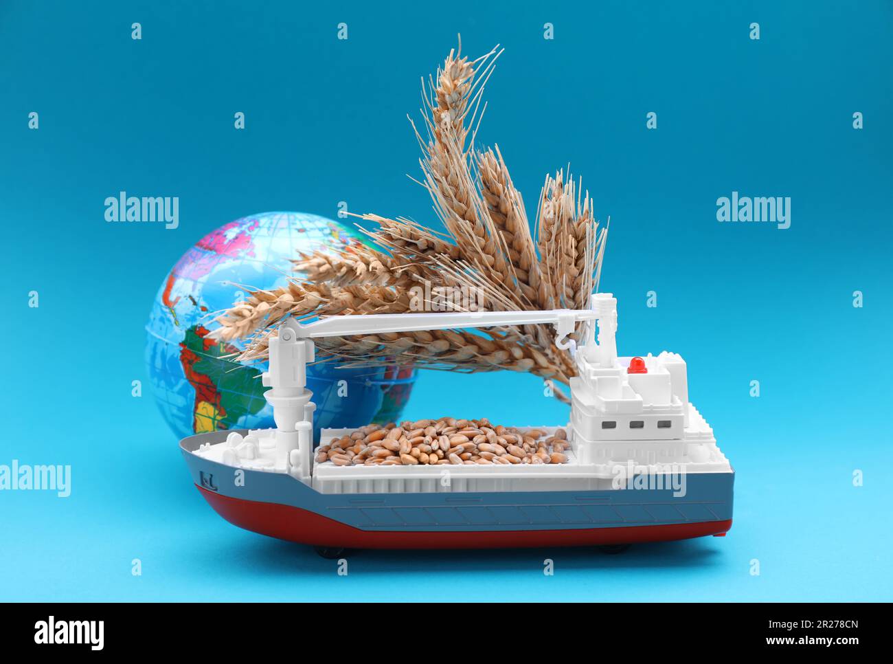 Globe, ears of wheat, toy cargo vessel on light blue background. Import ... Globe, ears of wheat, toy cargo vessel on light blue background. Import ...
