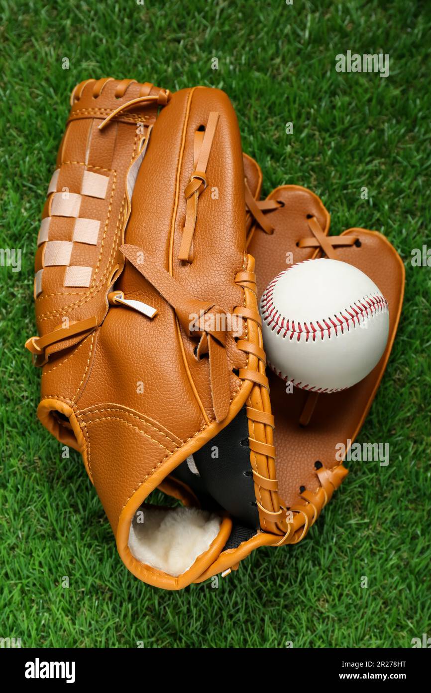 Catcher's mitt and baseball ball on green grass, top view. Sports game ...