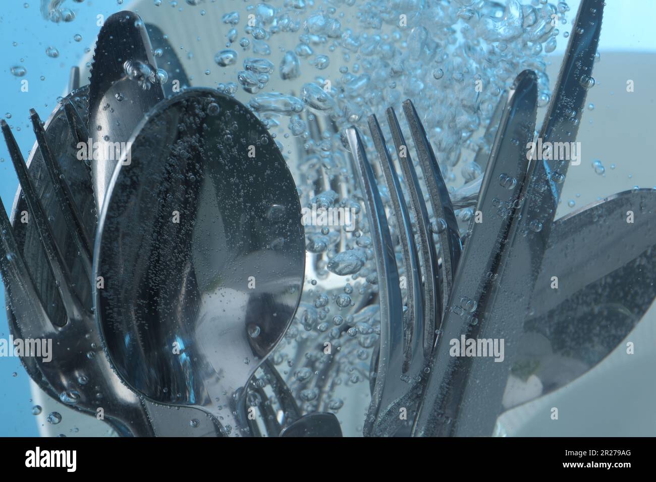 Washing silver cutlery in water on light blue background, closeup Stock ...