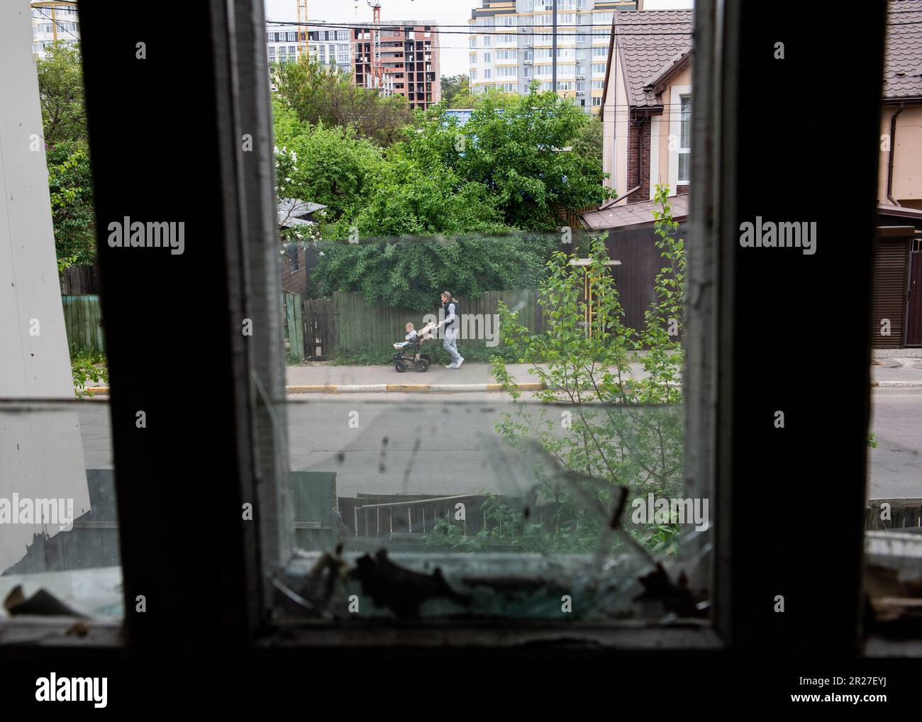 A woman is seen through a broken window of a destroyed home pushing a ...