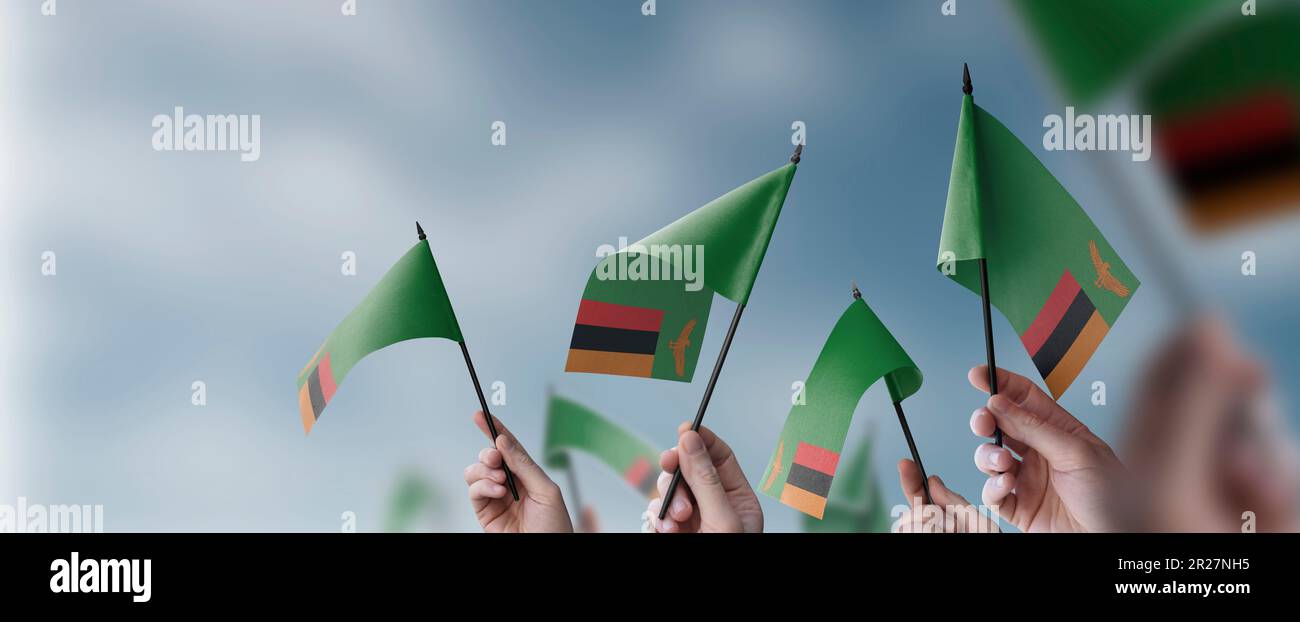 A group of people holding small flags of the Zambia in their hands ...