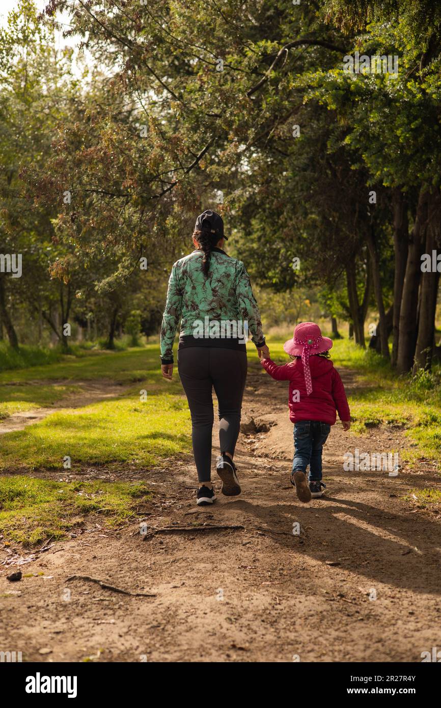 little daughter with her mother taking a walk during the day in a park ...