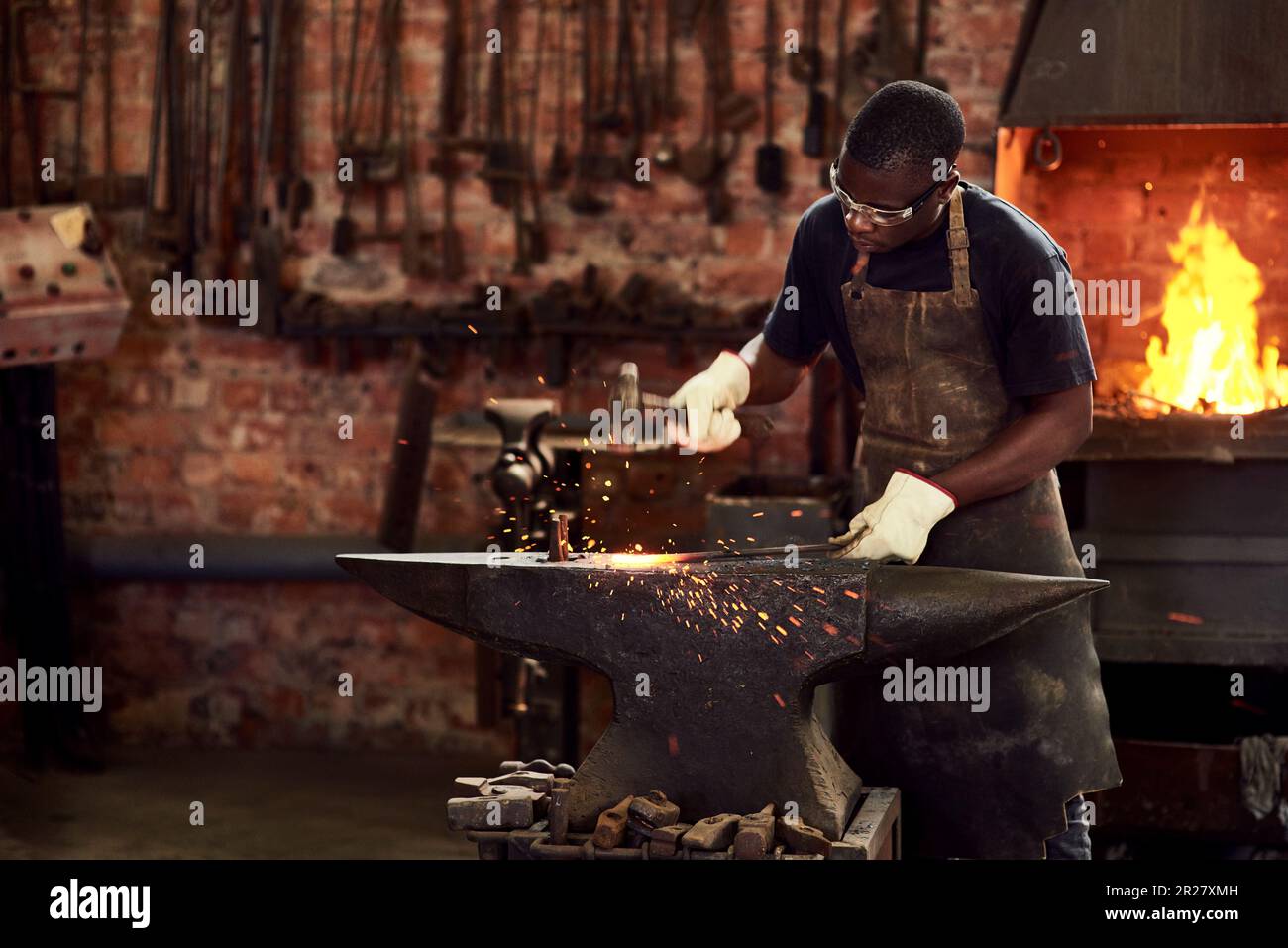 Blacksmith, worker and metal forge in workshop and manual industry ...