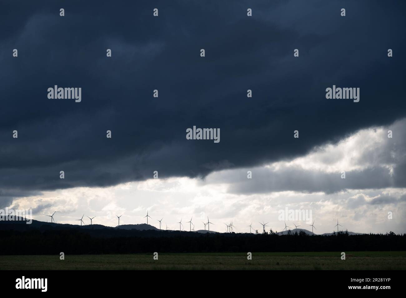 View across a harvested hay field onto a distant tree-lined hillside on ...