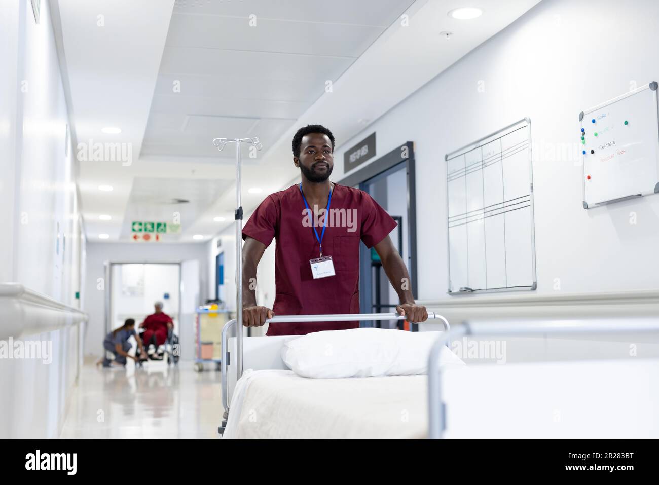 African american male medical worker pushing empty bed in hospital ...