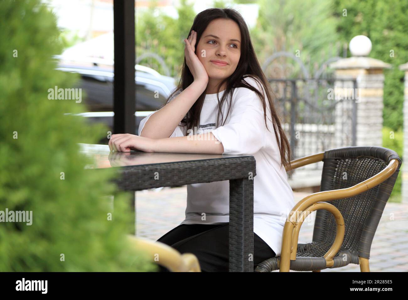 A beautiful teenage girl sits at a table in a cafe. A teenage girl is ...