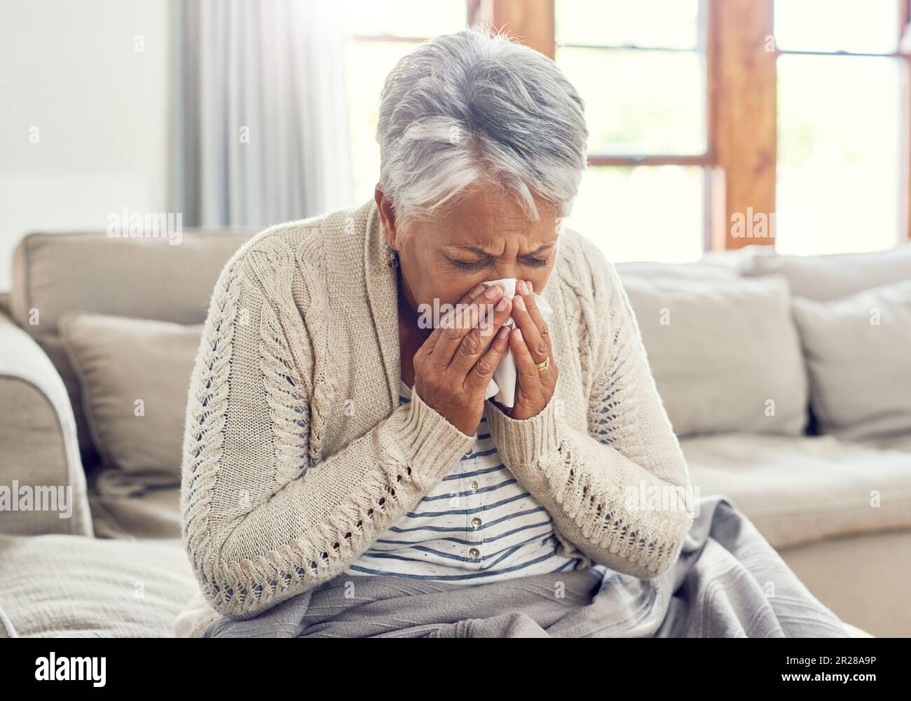 Senior woman, sick and blowing nose at home from virus, allergy and ...