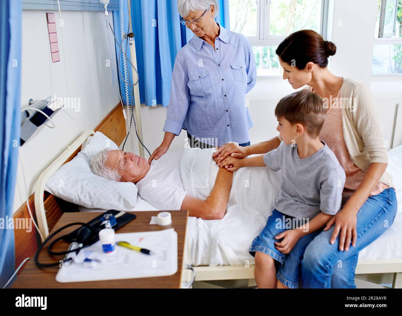 Coming together for granddad. a sick man in a hospital bed surrounded ...