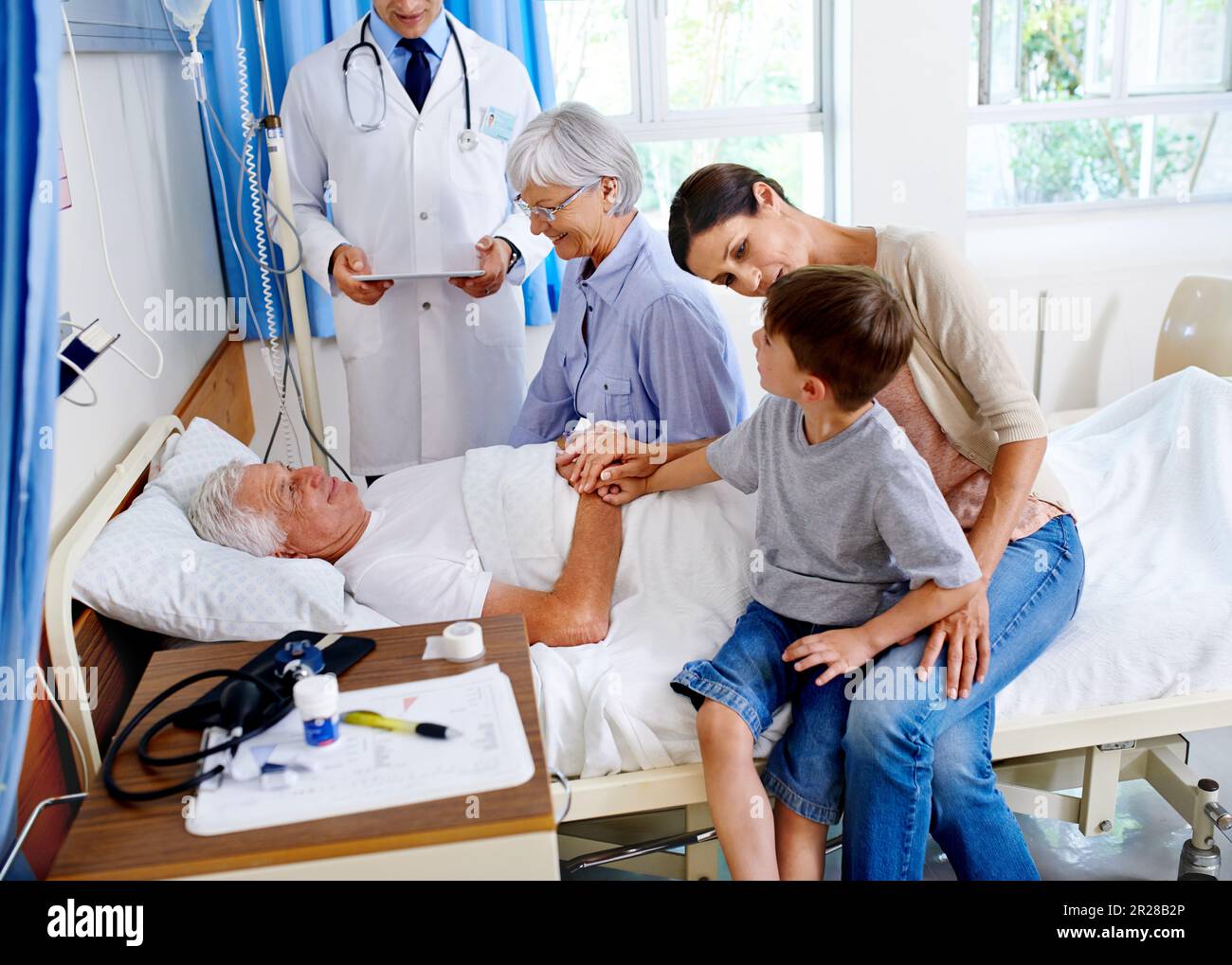 Getting the good news together. a sick man in a hospital bed surrounded ...