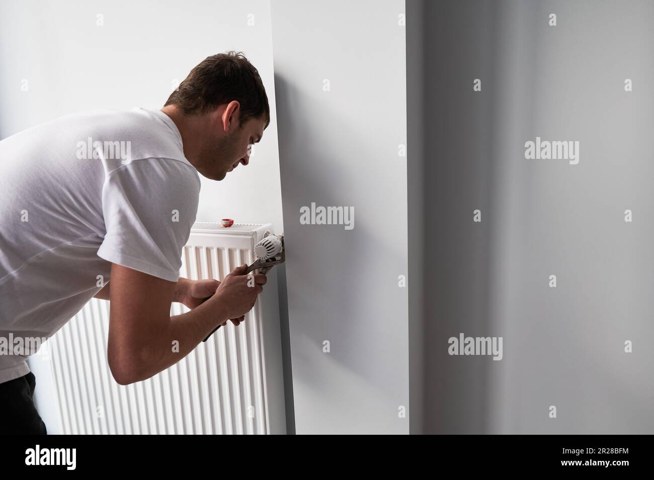 Male worker using wrench repair tool while installing heating radiator ...