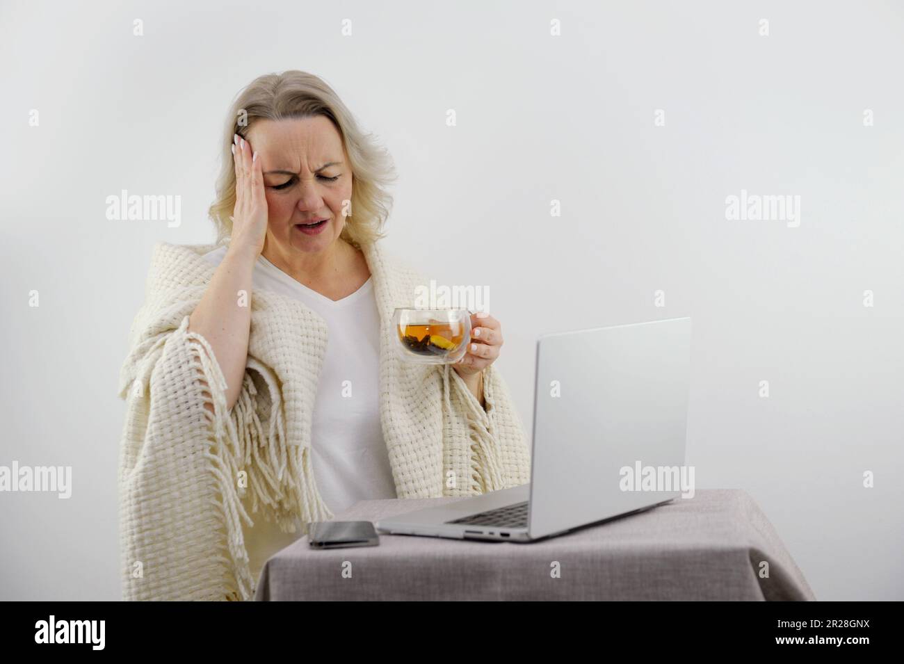 Ill brunette girl is sitting at sofa and working remotely on laptop ...