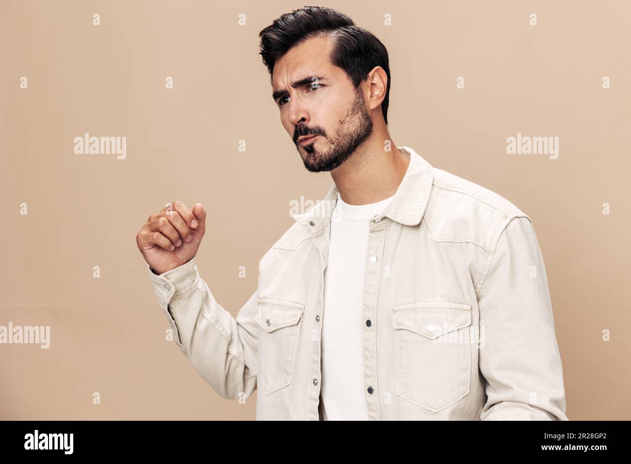 Portrait of a stylish man dissatisfied and angry screaming on a beige ...