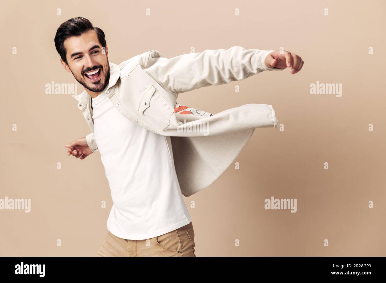 Stylish man smile runs and jumps on a beige background in a white t ...