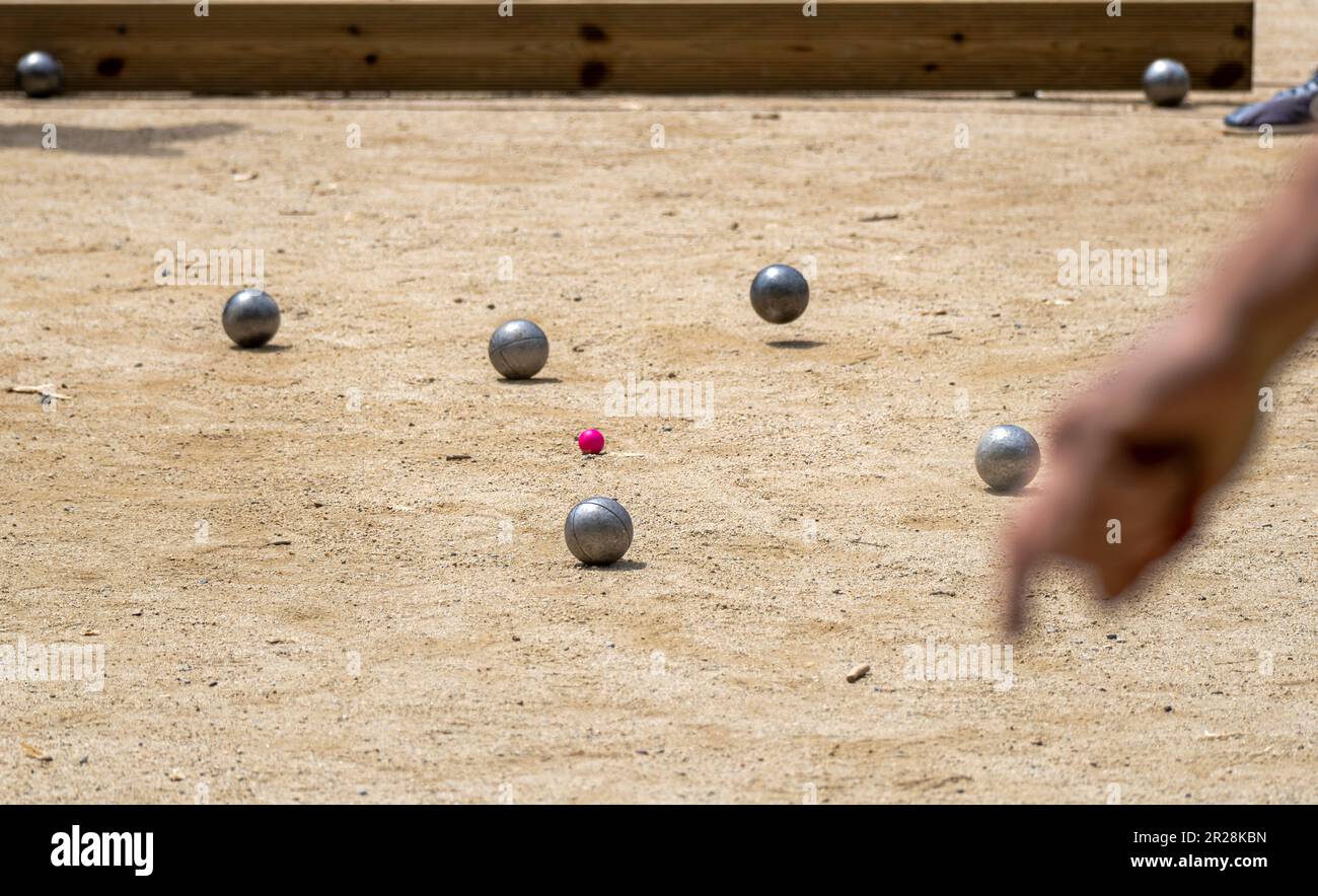 Silhouette of hand after throwing petanque ball on the sandy track to ...