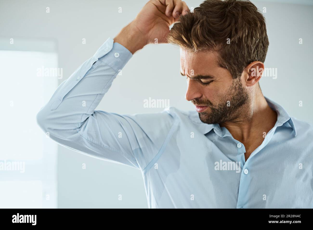 Shirt, stress with man smelling armpit sweat stain and indoors at his ...