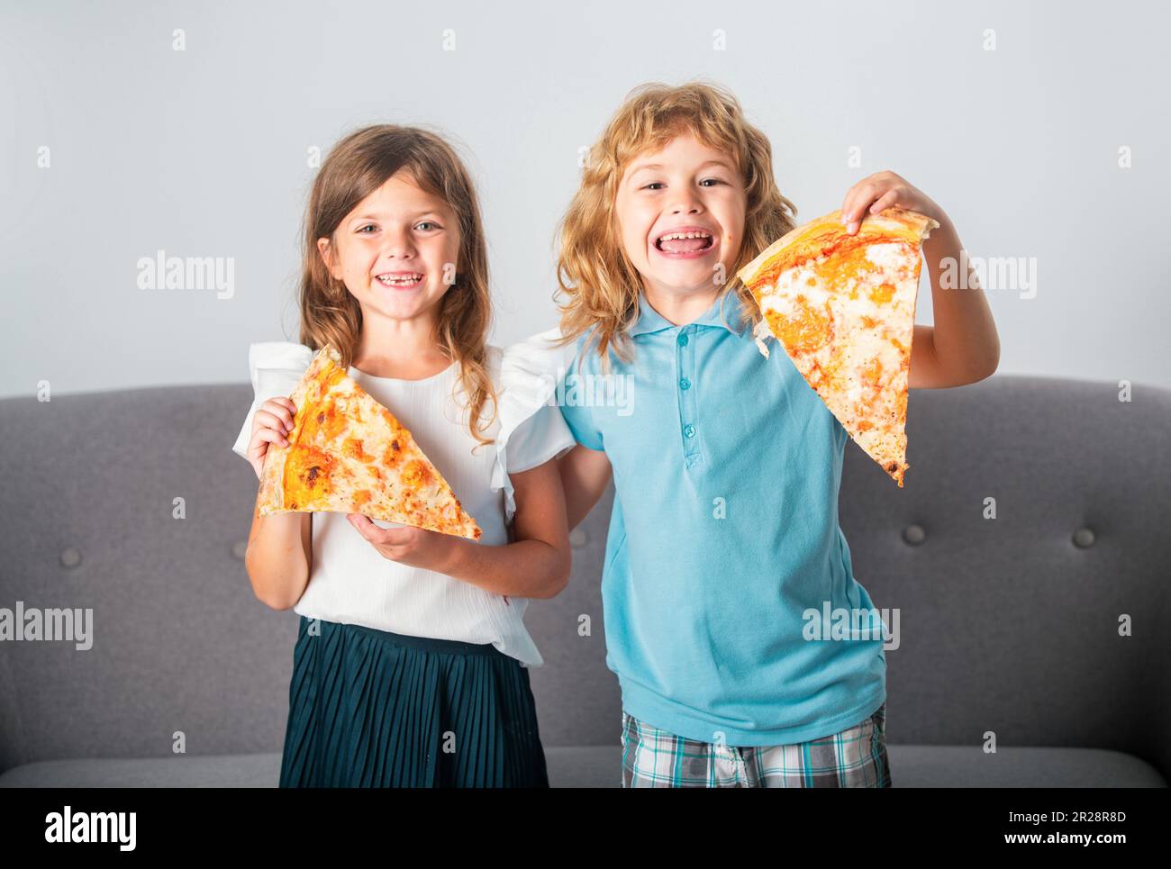 Two children eating pizza and smiling indoors. Happy smiling kids ...
