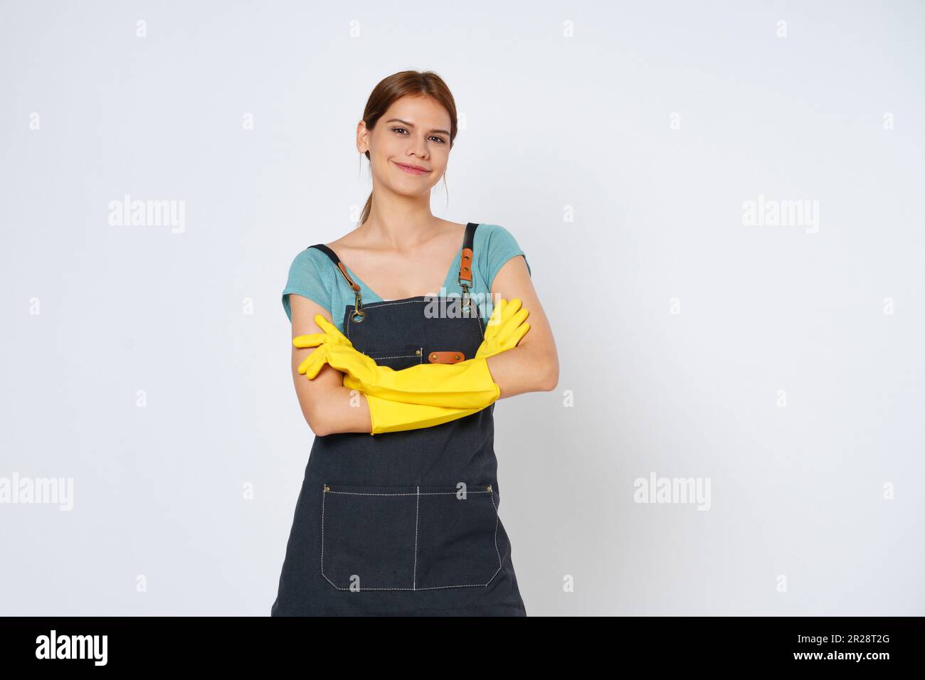 Young woman wearing yellow rubber gloves standing with arm crossed ...