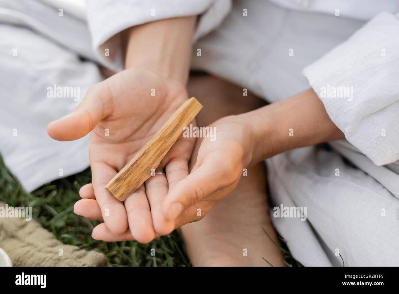 partial view of man in white linen clothes holding aromatic palo santo ...