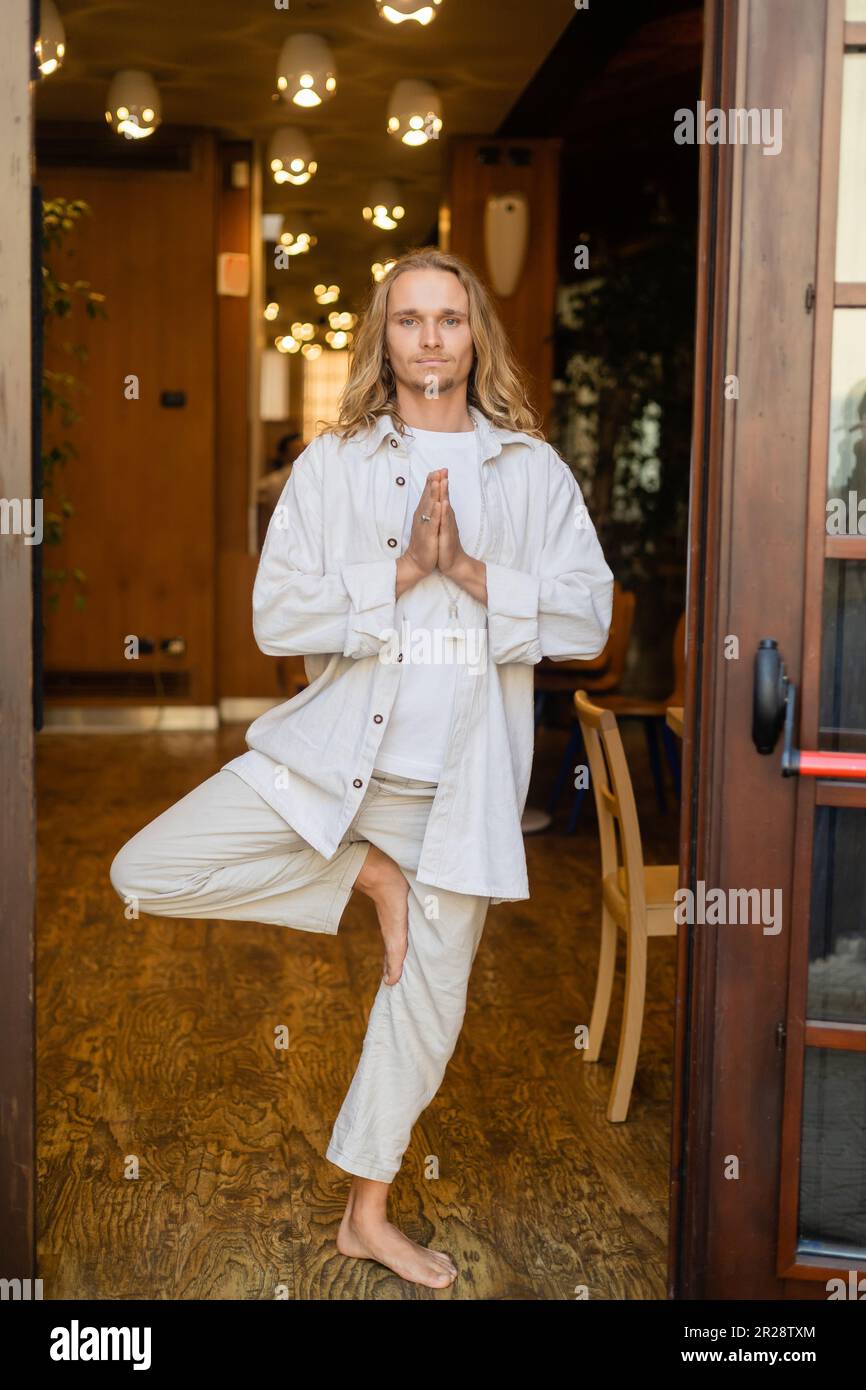 full length of barefoot man in white linen clothes standing in tree ...