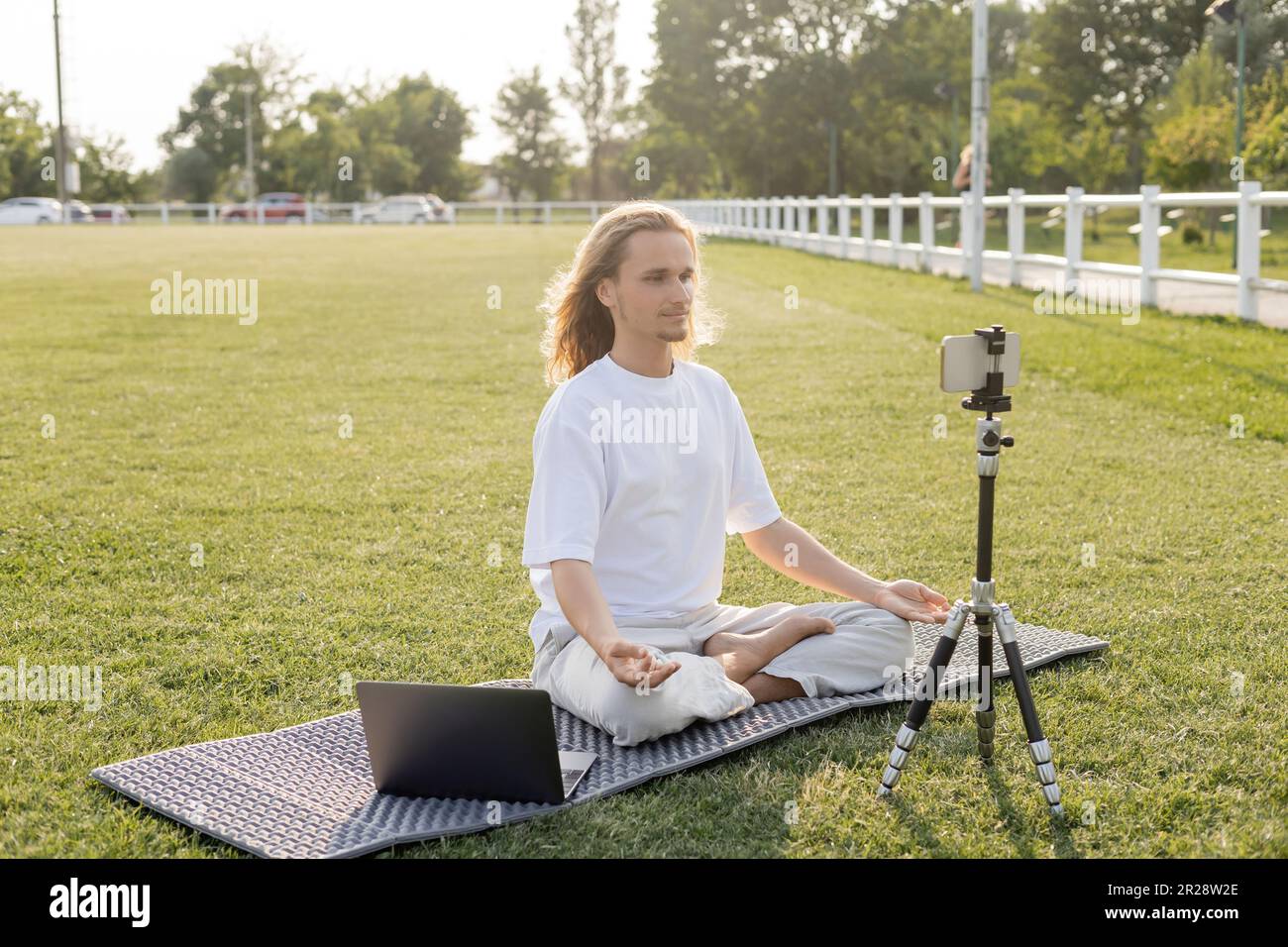 yoga vlogger meditating in easy pose near mobile phone on tripod on ...