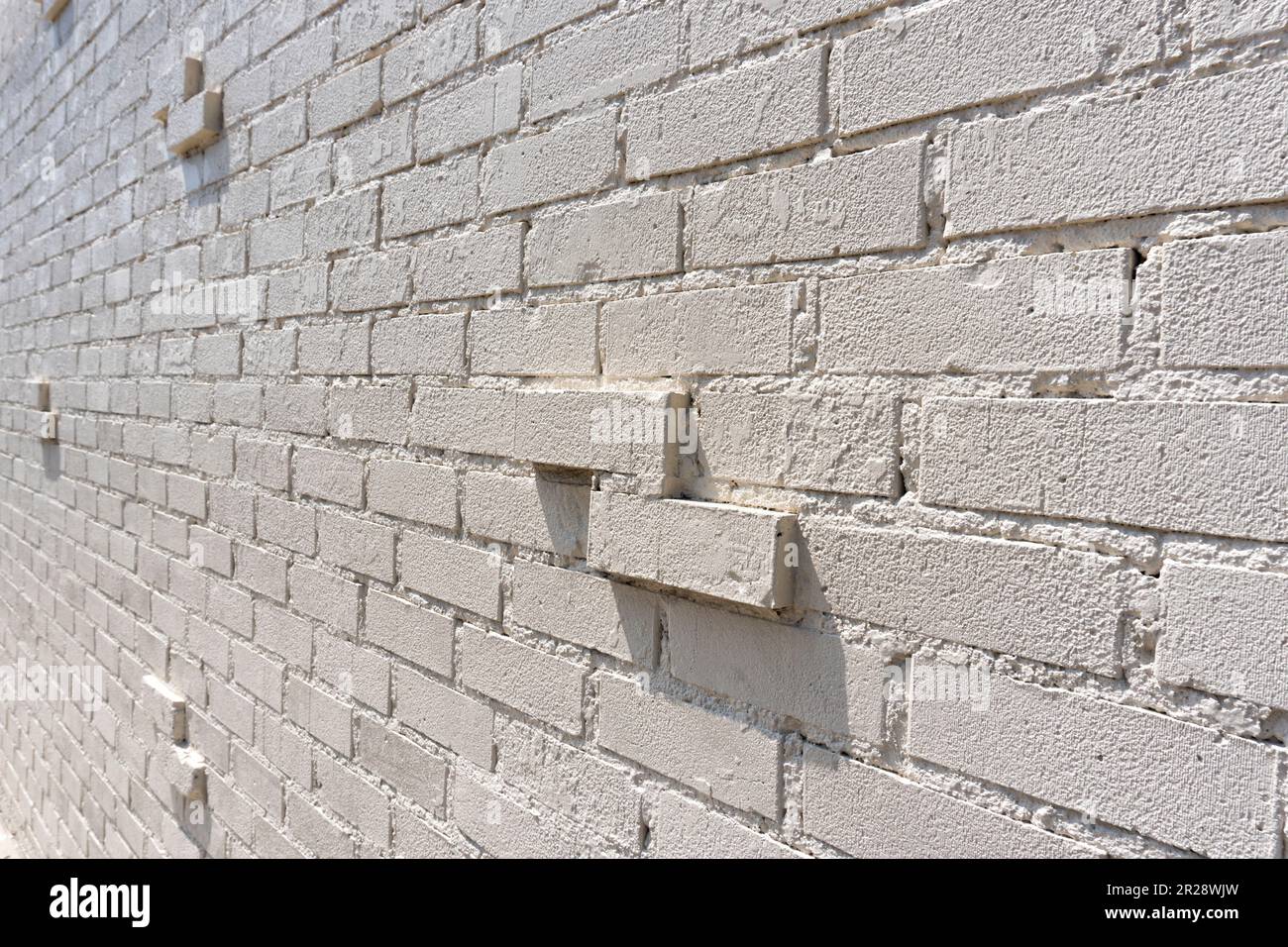 Beige brick wall with embossed bricks on sunny day Stock Photo - Alamy
