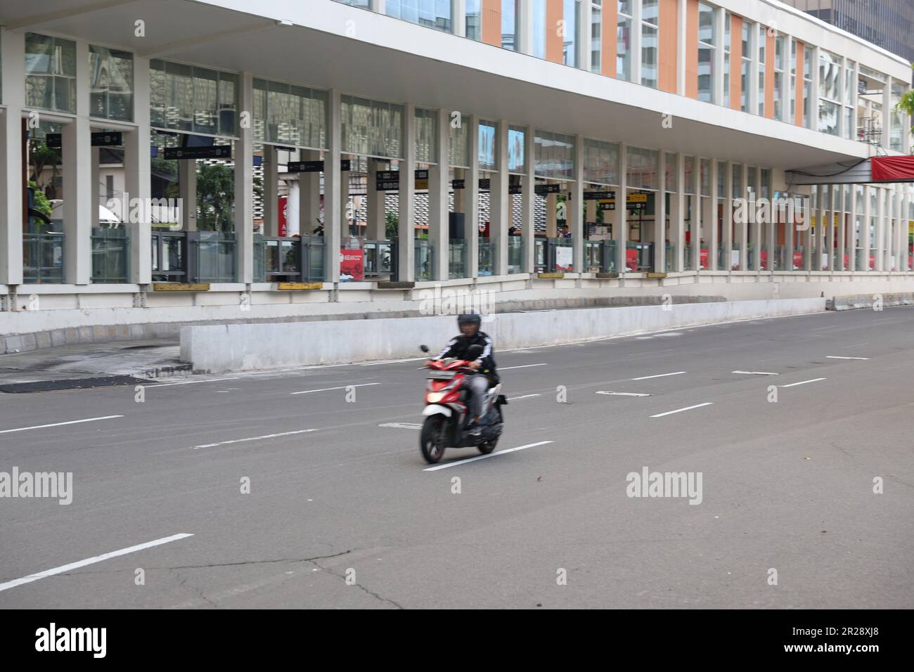Moped driver in empty Jakarta street Stock Photo - Alamy