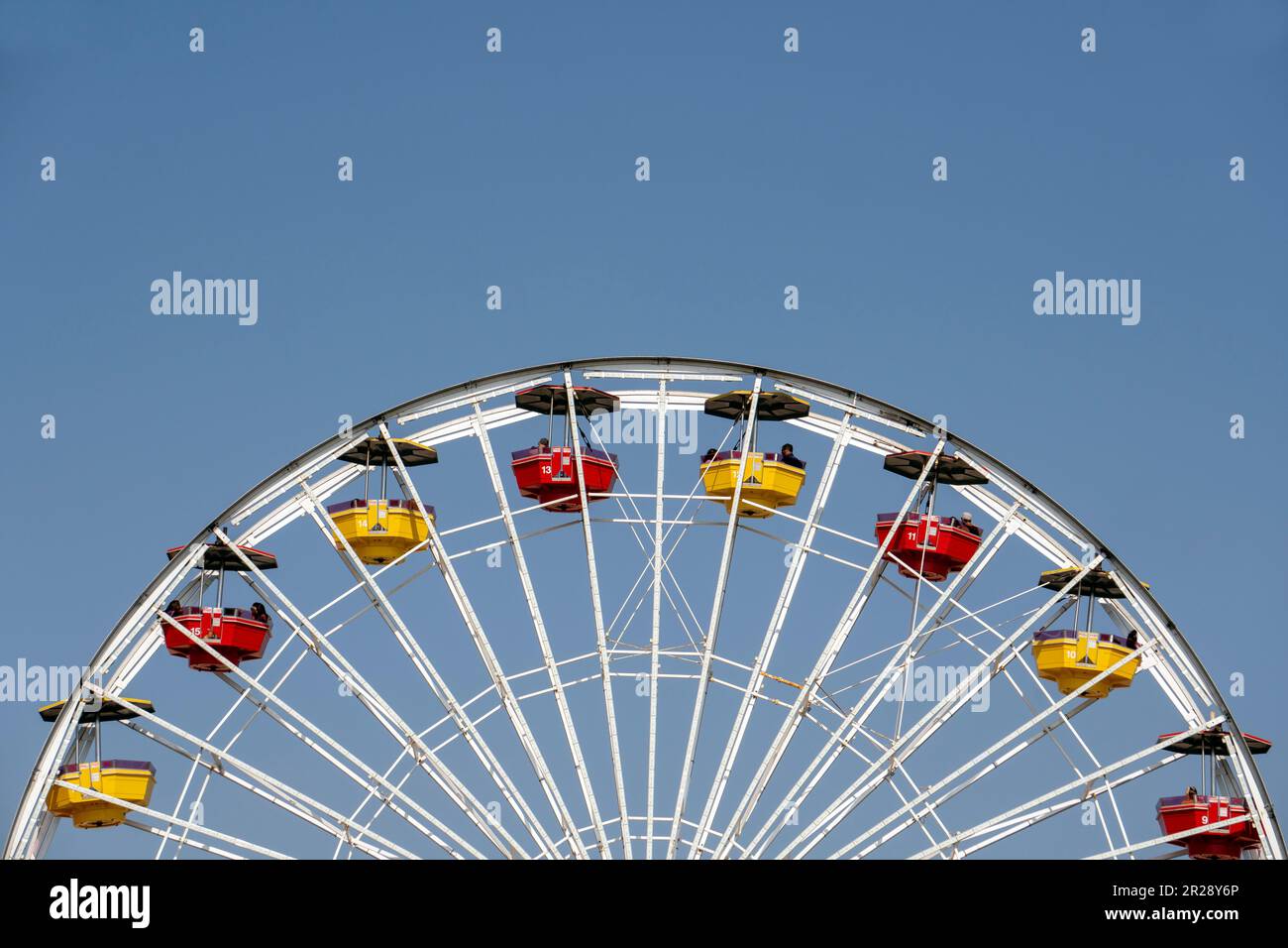 A view of a the top half of a Ferris Wheel with colorful cabins on a ...
