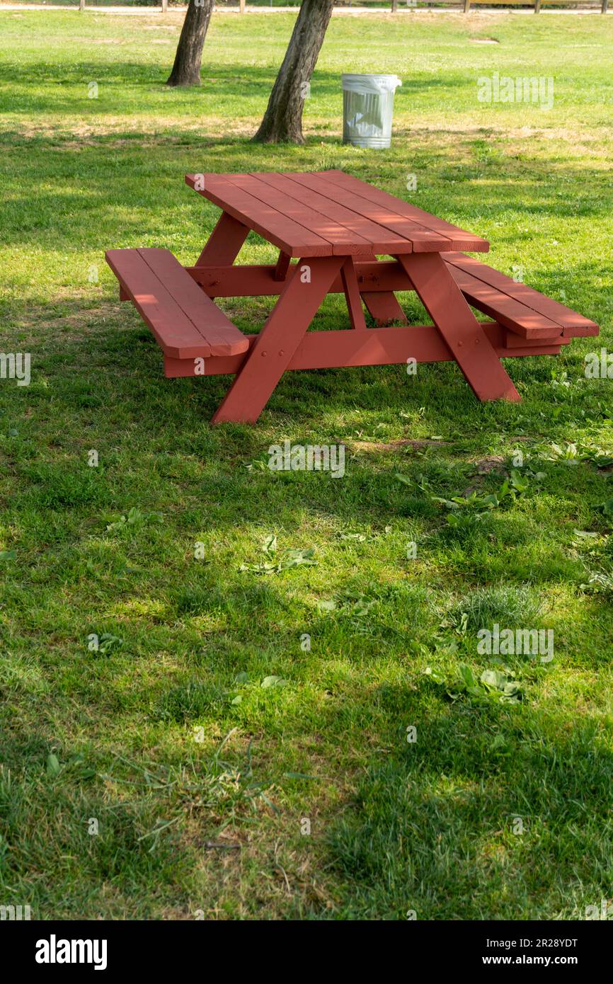 Picnic area with red table, trees and trash can in the park Stock Photo ...