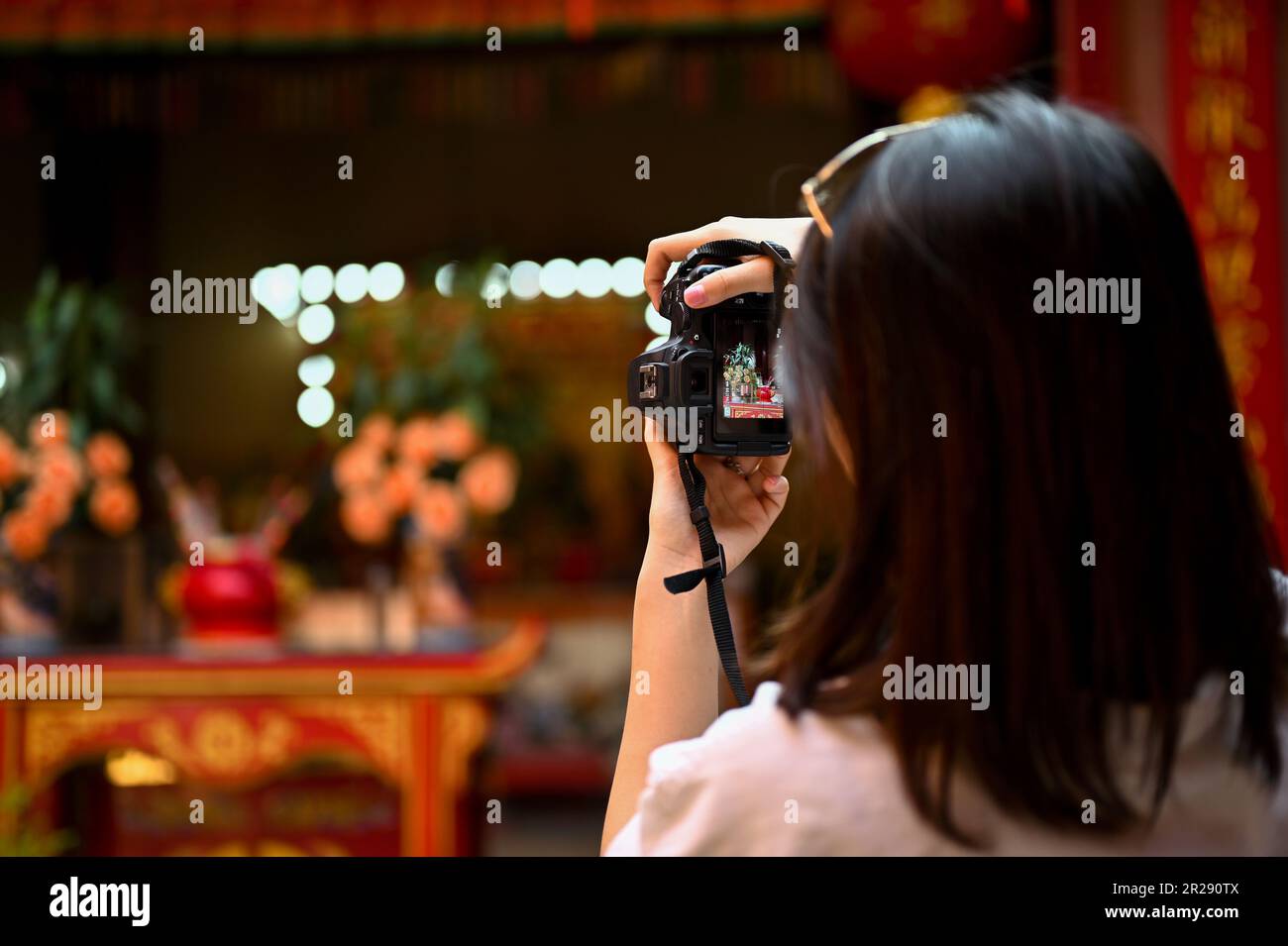 A young Asian female tourist uses her camera to take a photo of a ...