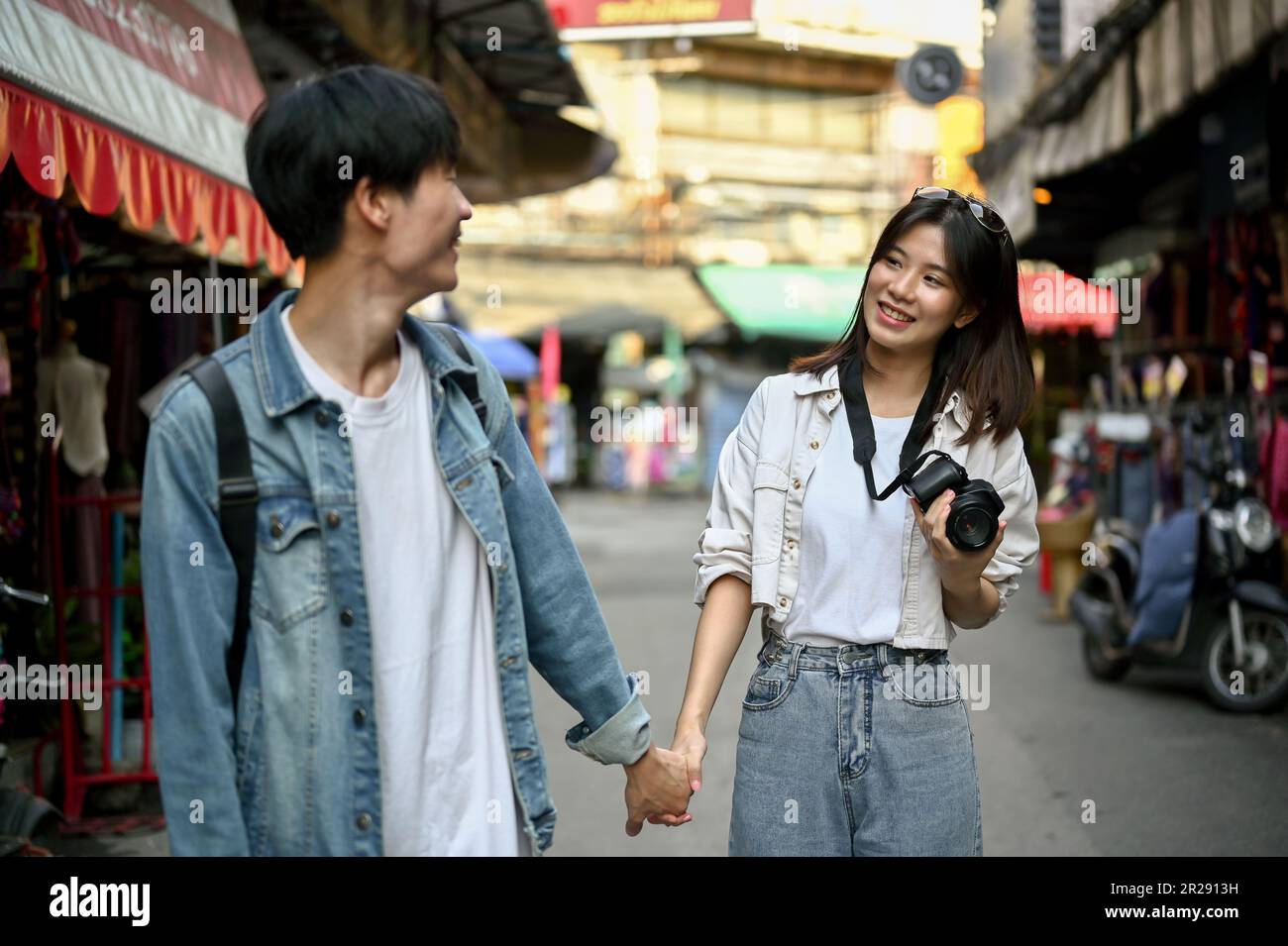Lovely and happy young Asian tourist couple holding hands while ...