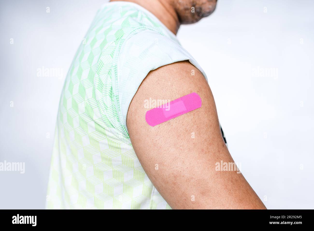 A pink bandage is attached to the man's arm. Concept for first aid ...