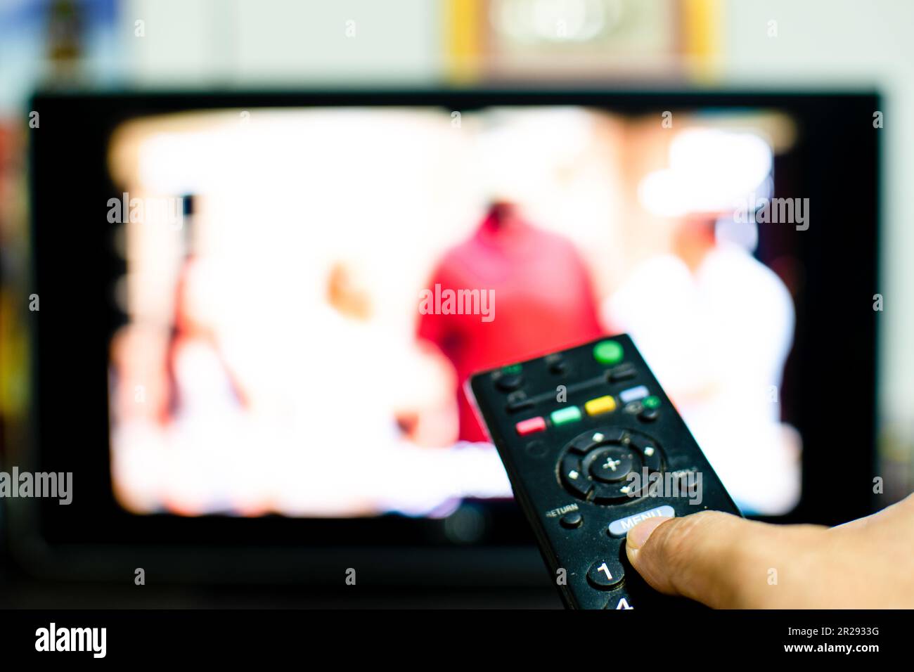 The man's holding and pressed the remote control to turn on the TV and ...