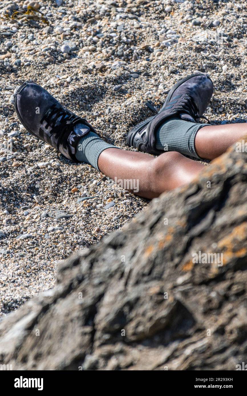 The legs of a walker resting on the beach at Little Fistral in Newquay ...