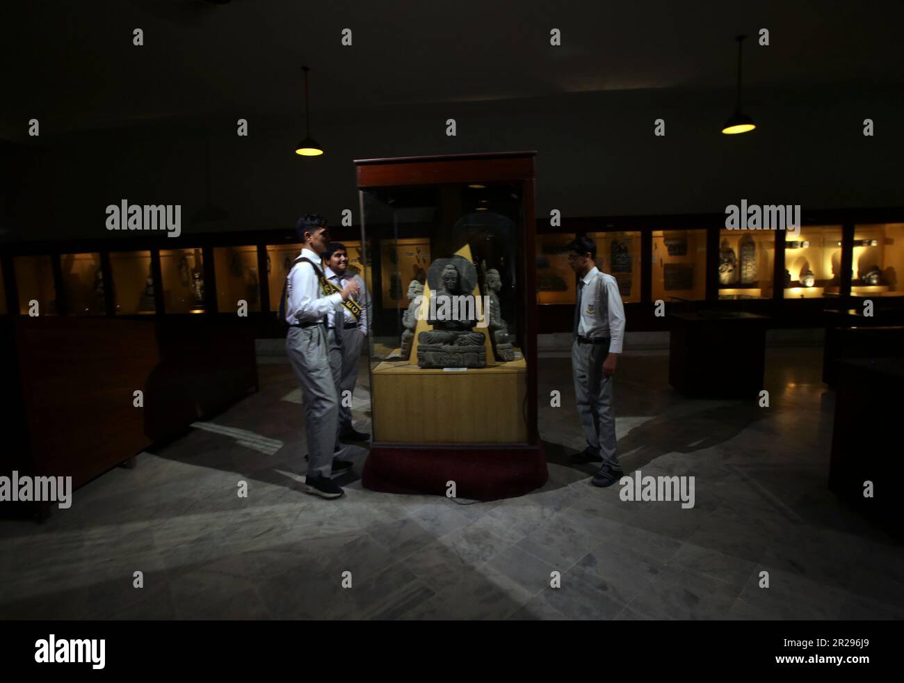 Visitors look at artifacts displayed in glass cases at the Peshawar ...